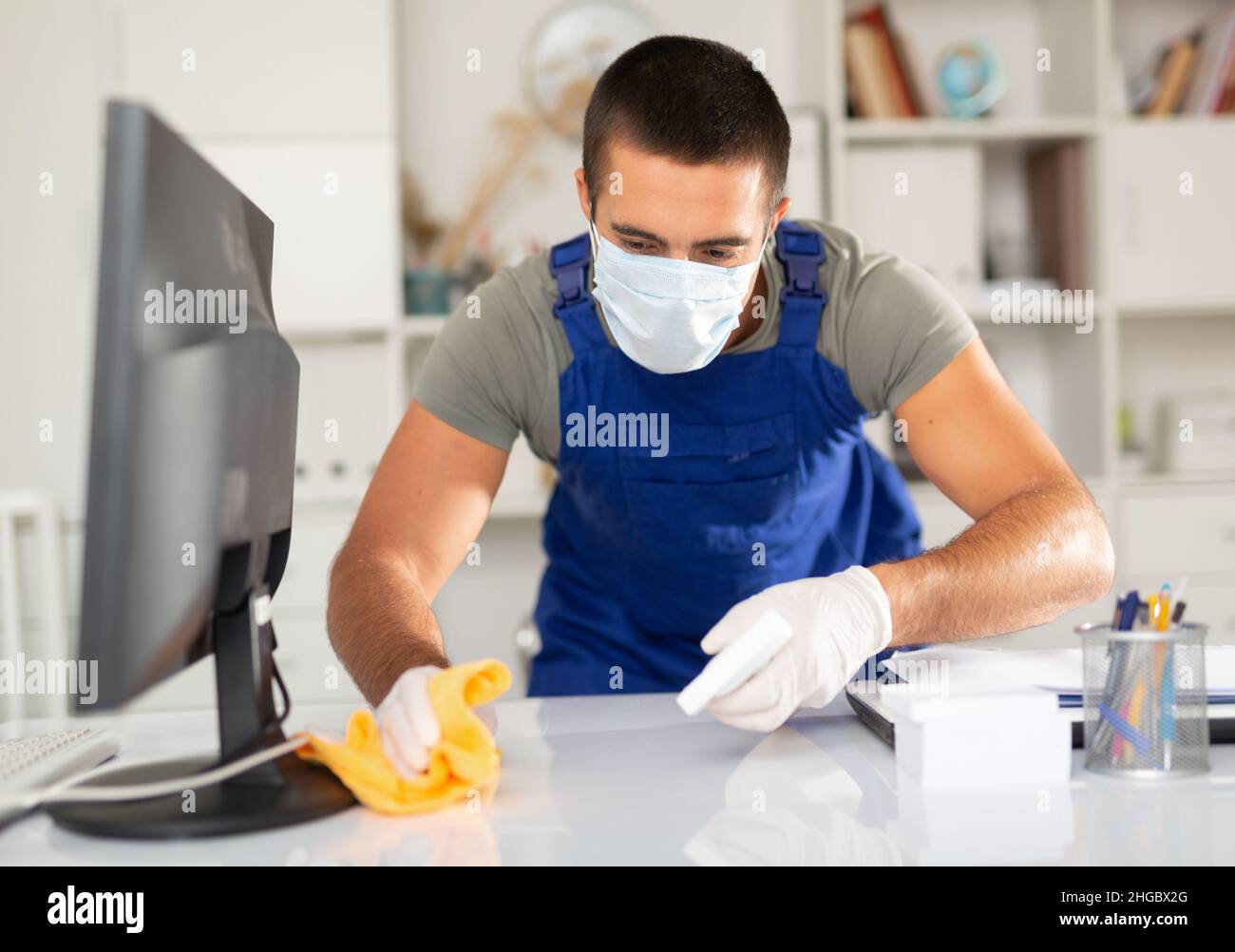 Male cleaner in protective medical mask does cleaning in office Stock ...