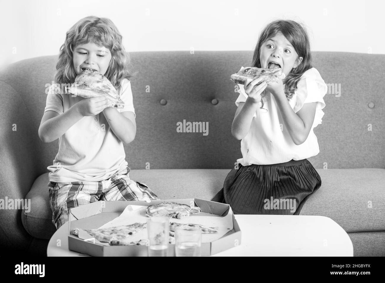 Funny cute children girl and boy eating tasty pizza. Hungry children ...