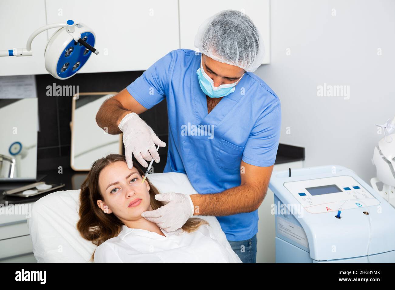 Beautician performing face contouring injections to female patient ...