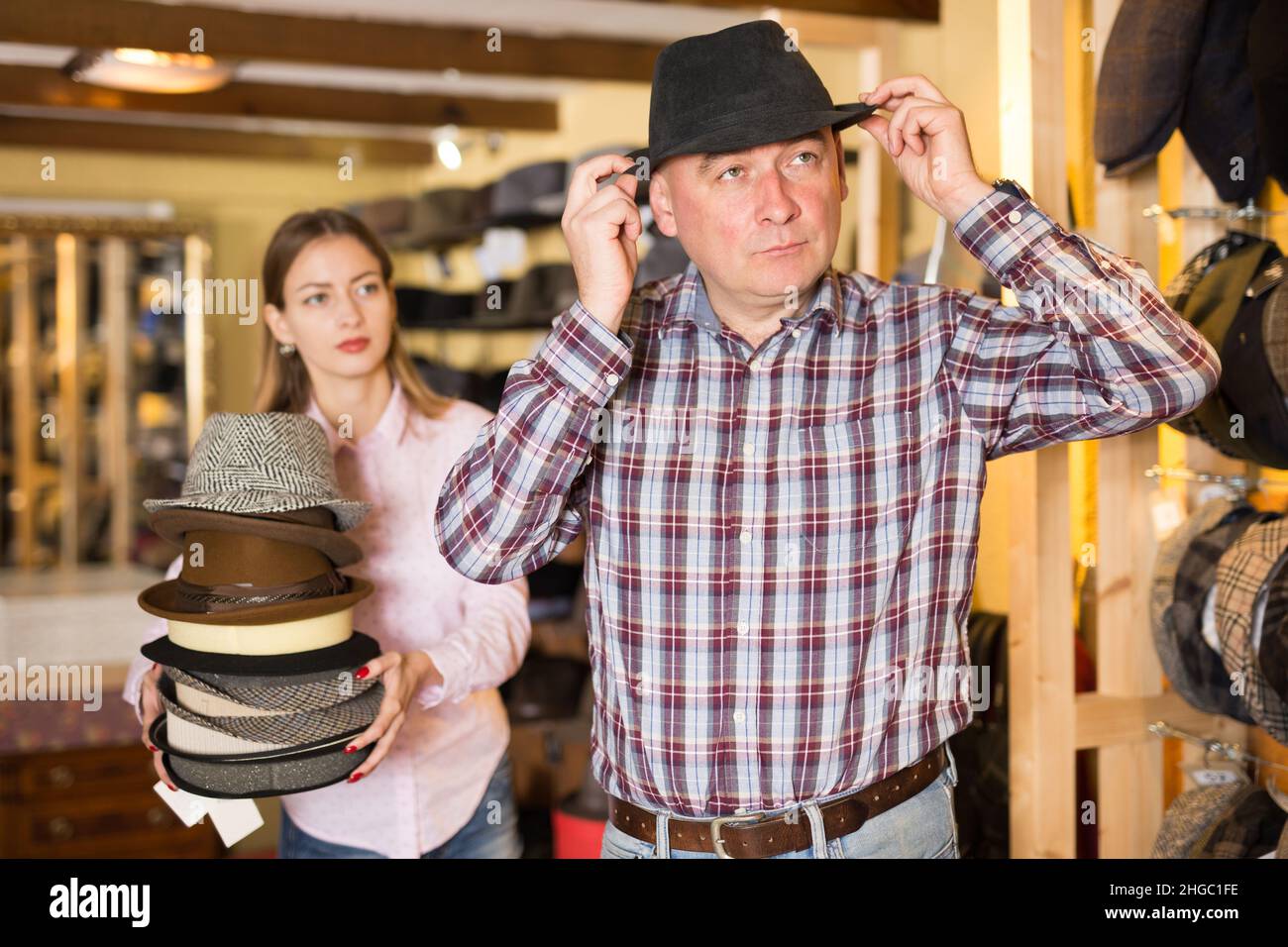 Man trying on hat in shop Stock Photo - Alamy