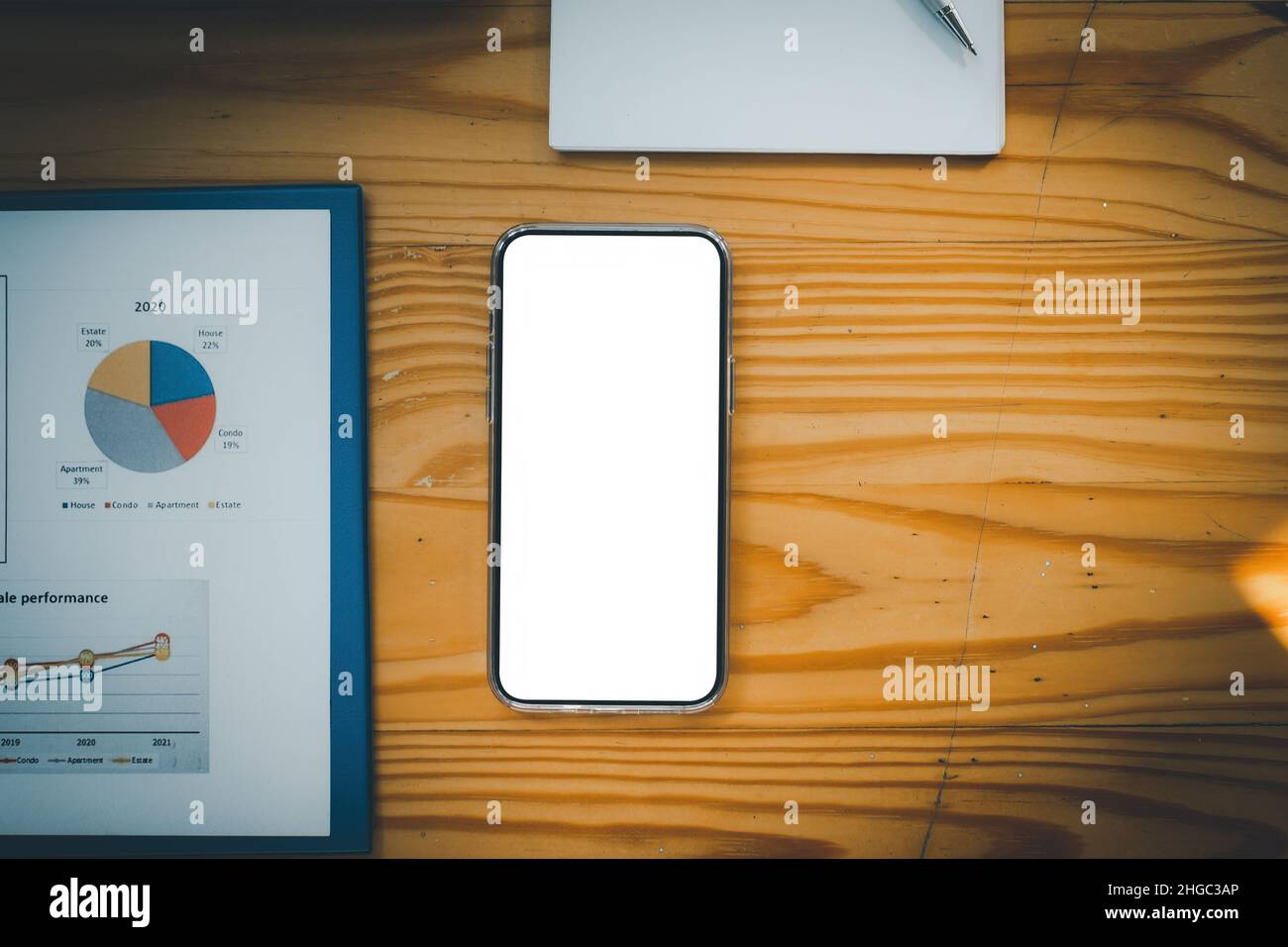 Mock up mobile phone white screen with financial chart on wooden desk ...