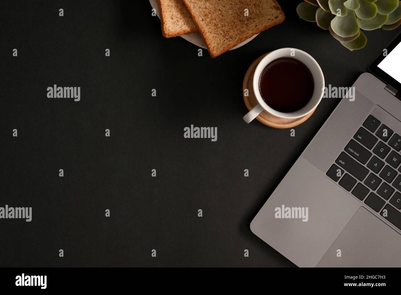 Modern black workspace background with laptop computer, coffee cup toasts and copy space. top ...