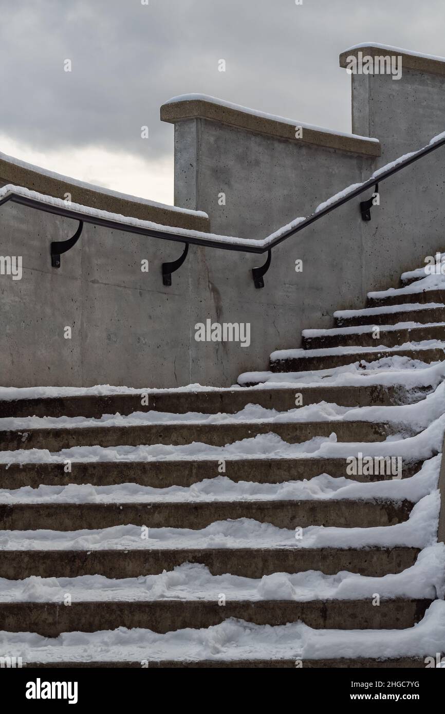 Stone concrete snow-covered stairs with footprints in the city in ...