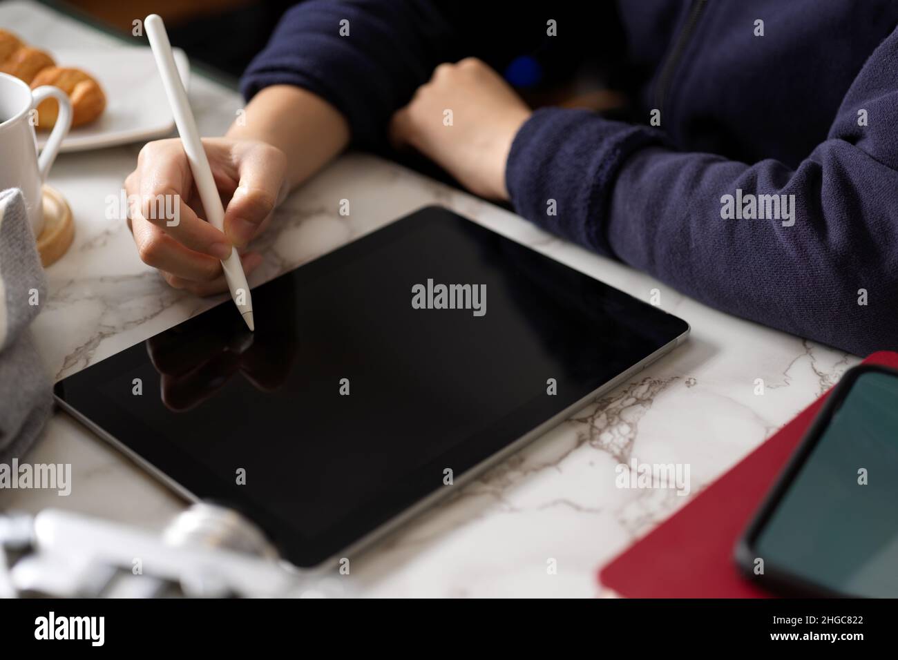 A female drawing on digital tablet computer with stylus pen on her ...