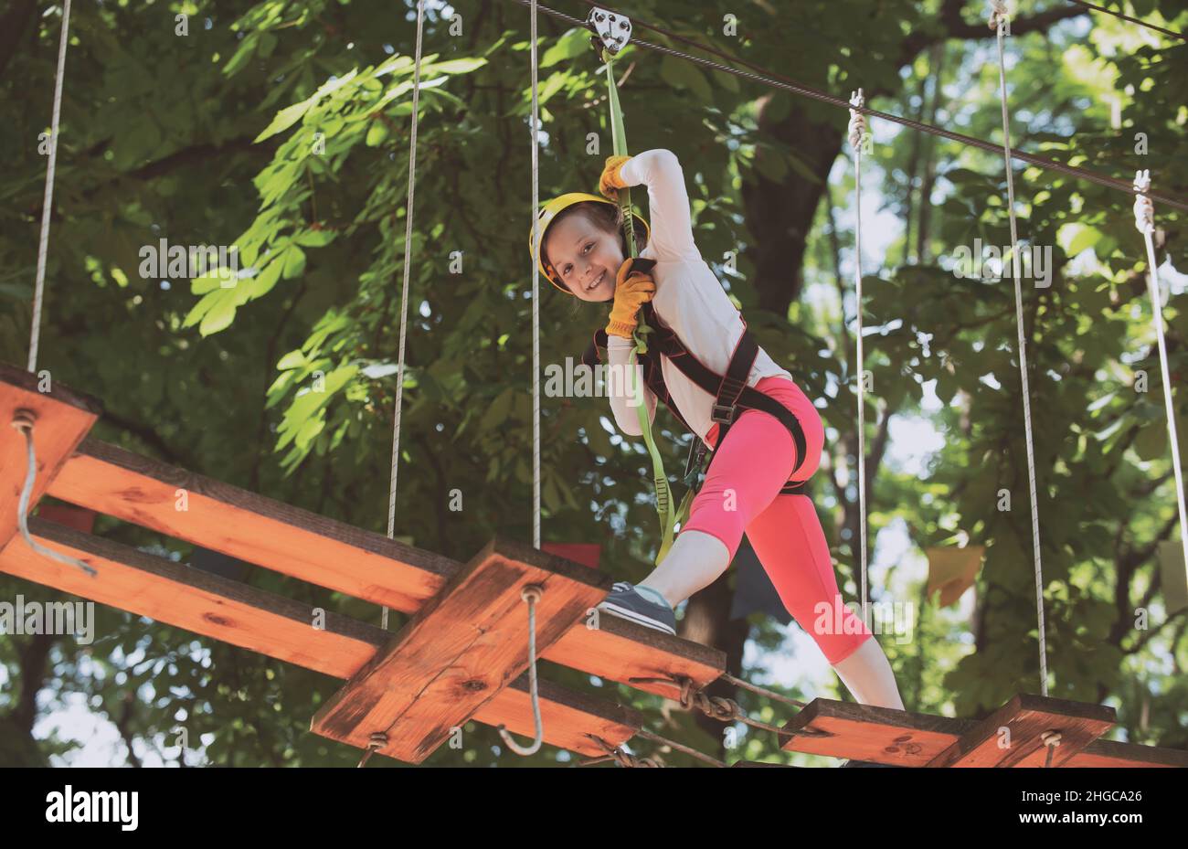 Cute school child boy enjoying a sunny day in a climbing adventure ...
