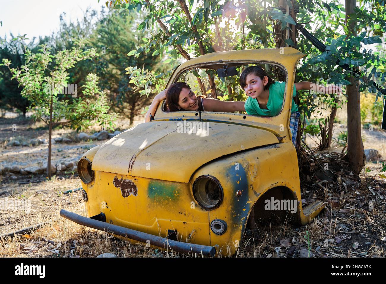 portrait of a mother and child playing inside the wreckage of a yellow ...