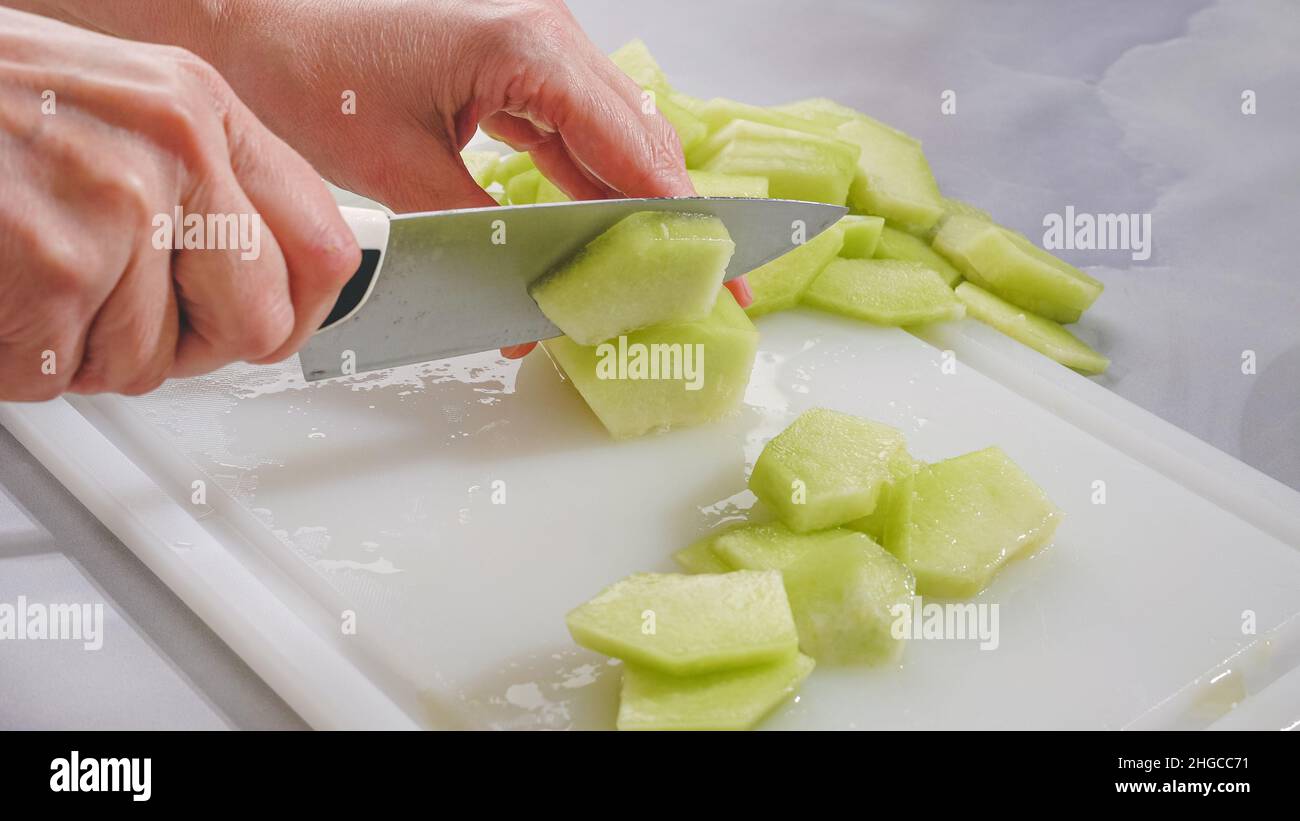 Honeydew melon close up on cutting board. Woman slicing melon, fruit ...
