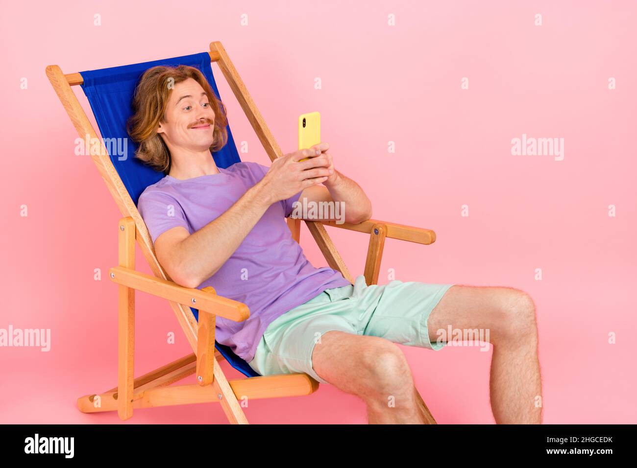 Portrait of handsome trendy cheery focused guy sitting in chair using ...