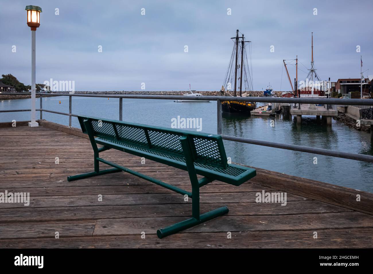 Empty public bench at the pier in Dana Point harbor on a foggy sunset ...