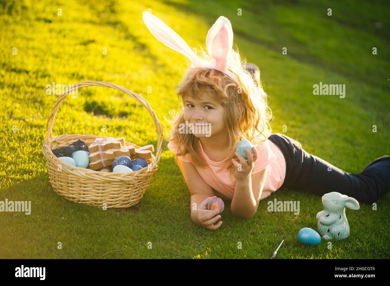 Child boy in rabbit costume with bunny ears hunting easter eggs on ...