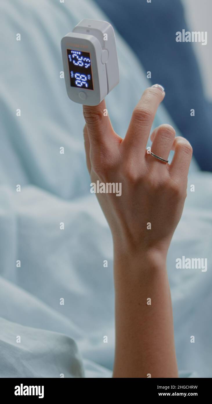 Close up of unwell woman holding oximeter on finger for oxygen ...