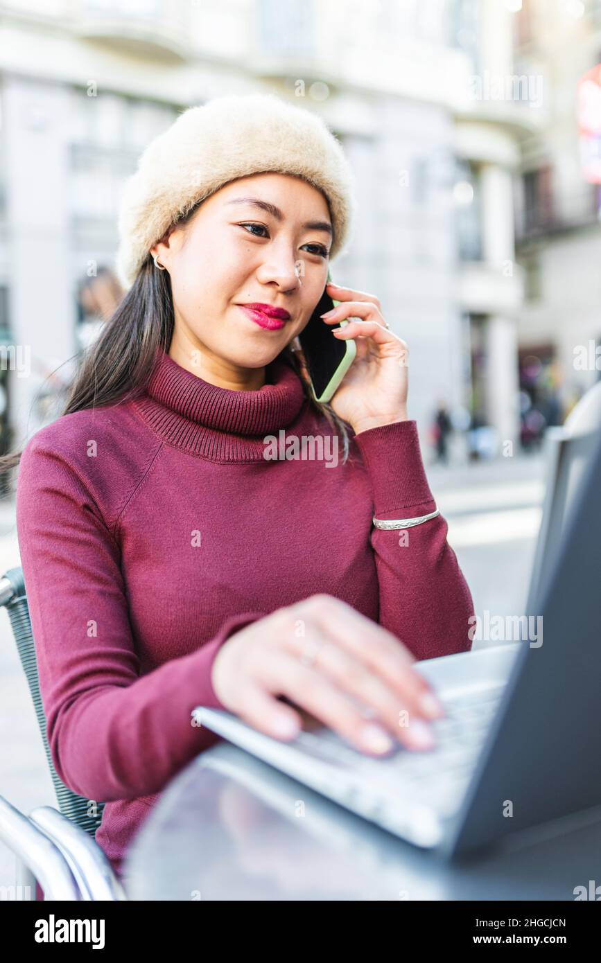 Content Chinese female having phone call and surfing modern netbook ...