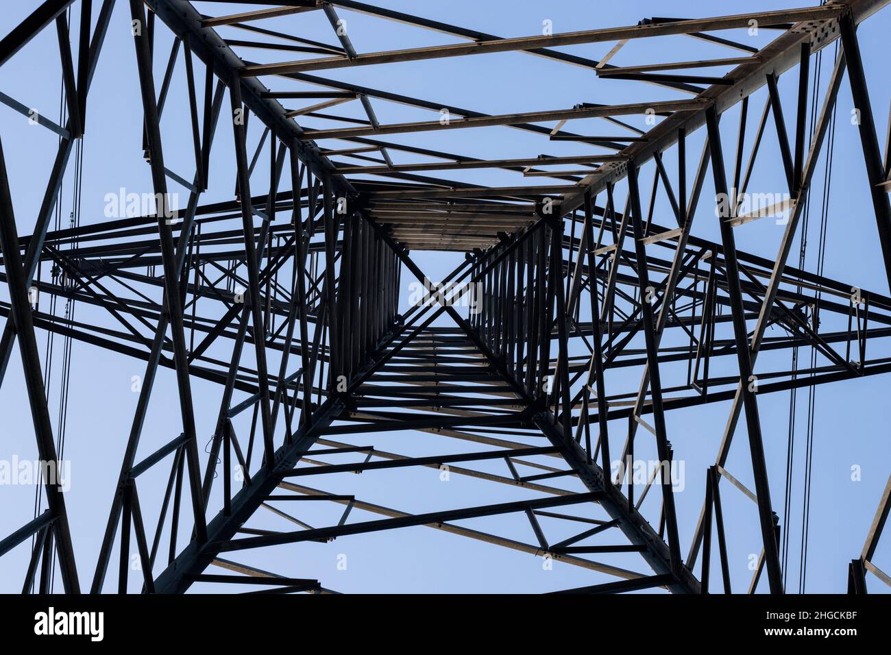High voltage electricity transmission tower bottom view under the blue ...