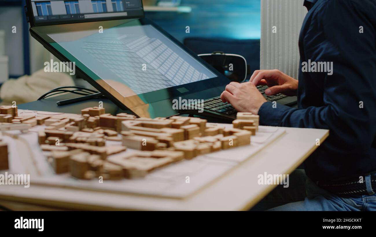 Close up of architect hands using touch screen computer and maquette on ...