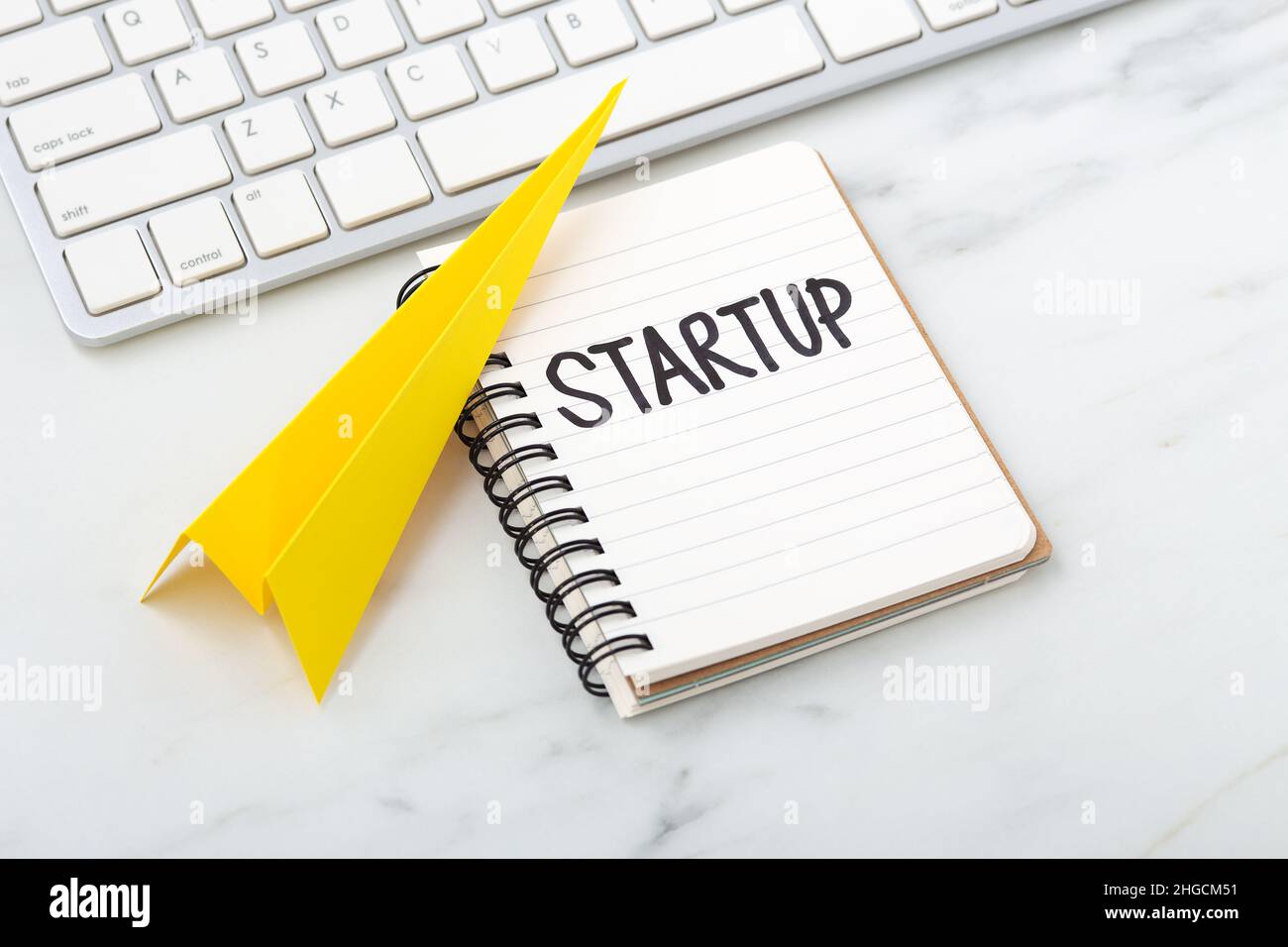 Paper rocket on notebook with startup text and computer keyboard ...