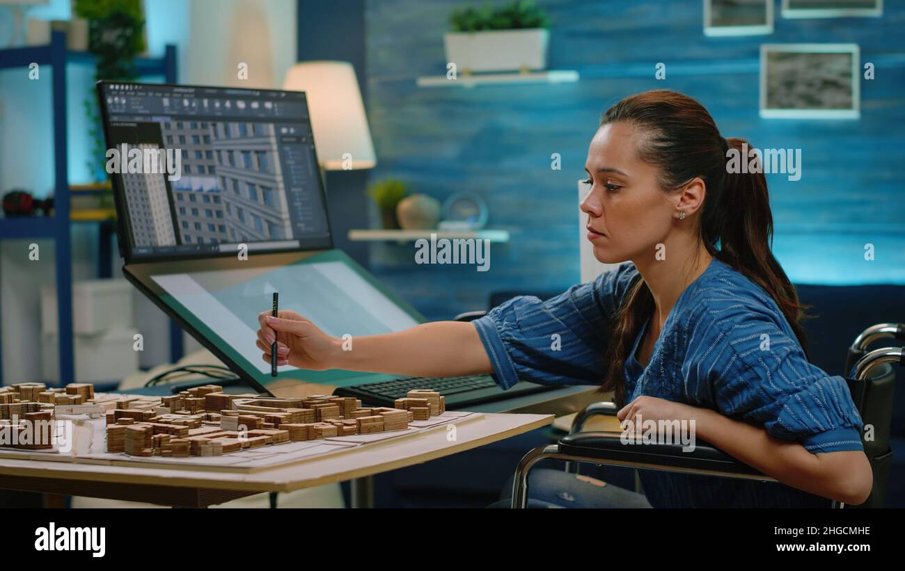 Invalid engineer looking at building model on computer designing layout ...