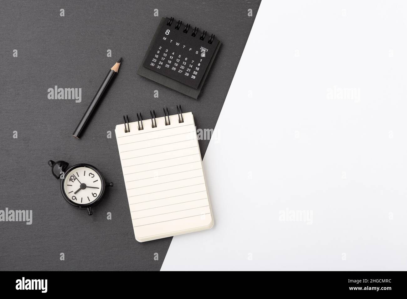 Calendar with notebook and alarm clock on black and white background ...