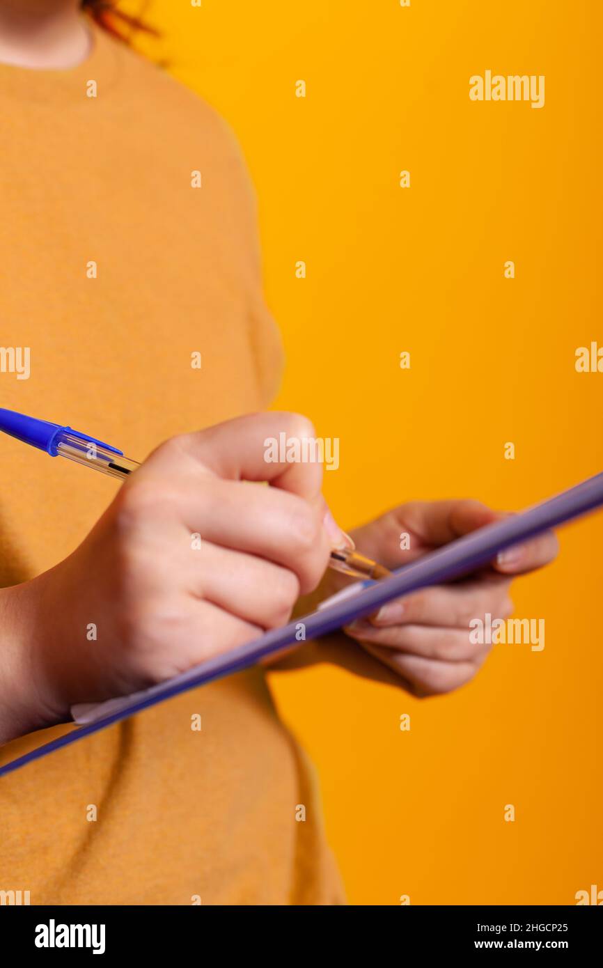 Close up of hand holding pen and writing on clipboard papers for ...