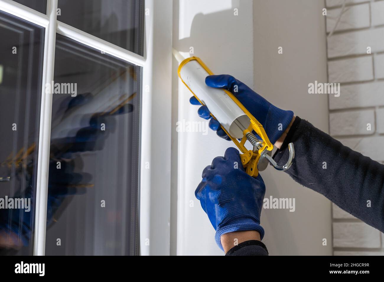 Worker is applying polyurethane foam to fill gap between sash and ...