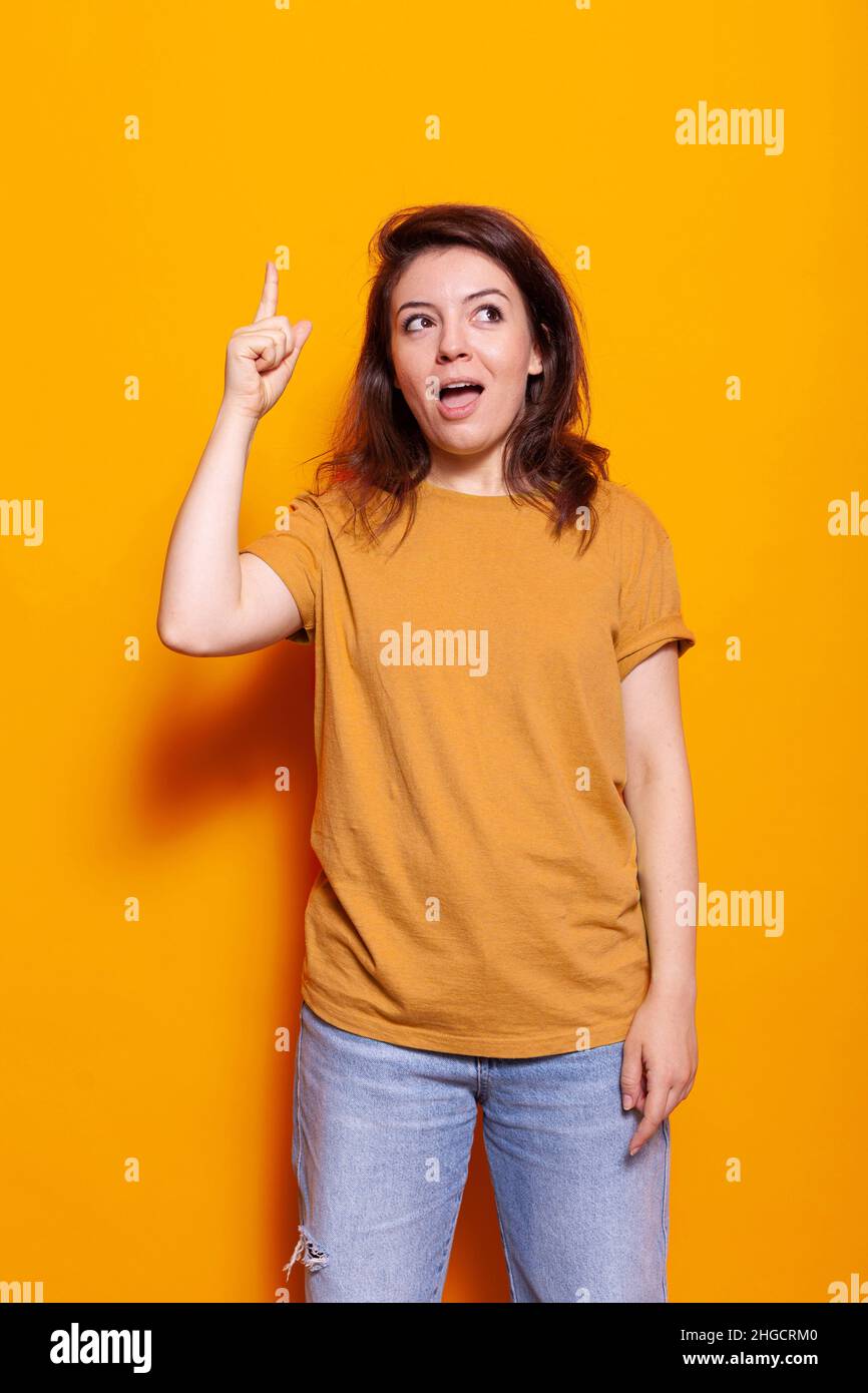 Positive woman using index finger to point up, standing over isolated ...