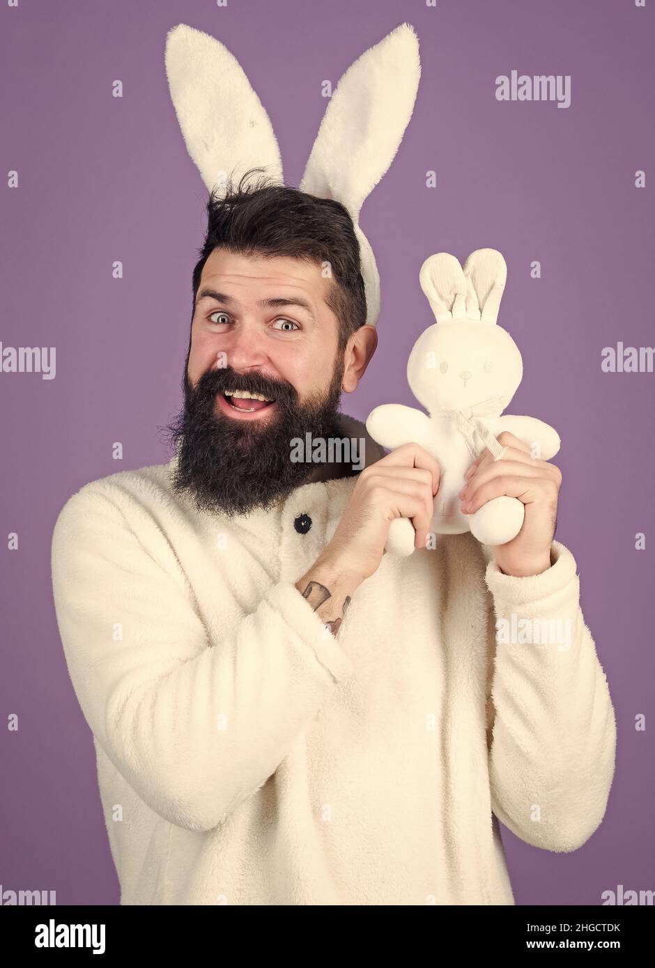 Having his own bunny. Happy man with rabbit ears kissing bunny toy ...
