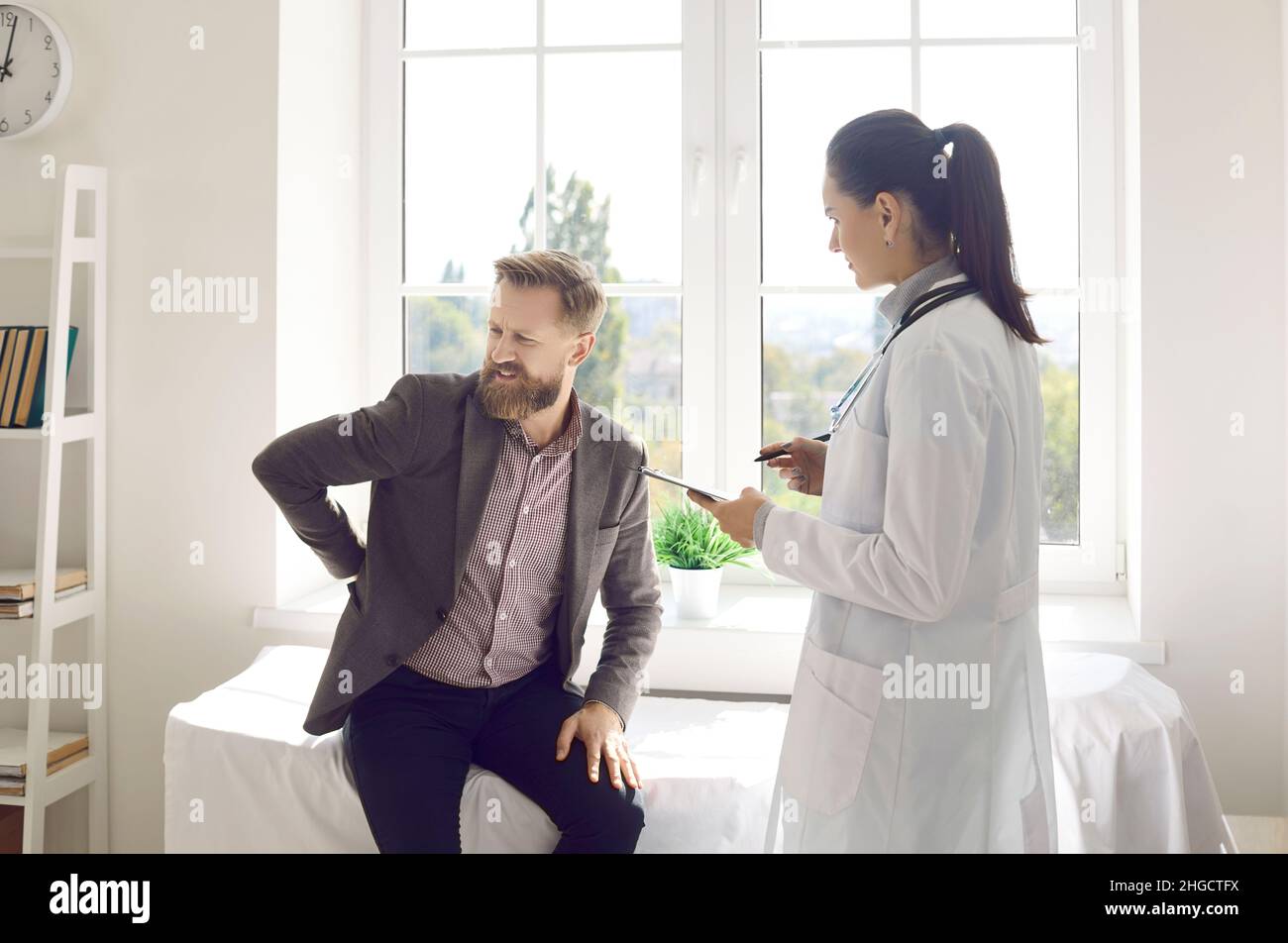 Young man who has back pain seeing his doctor and telling her about his ...