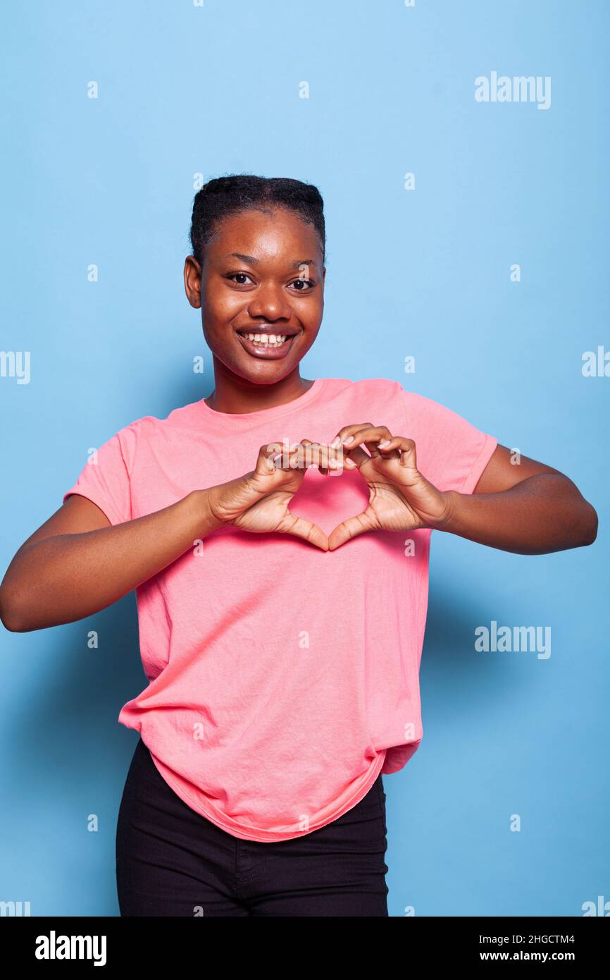 Portrait of african american student smiling at camera making heart ...