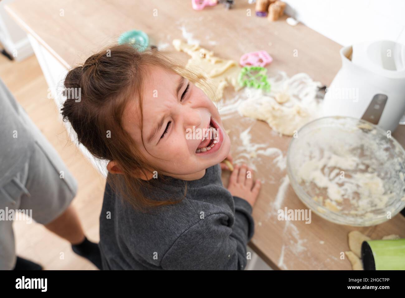 High angle view of the little crying child standing at the kitchen and ...