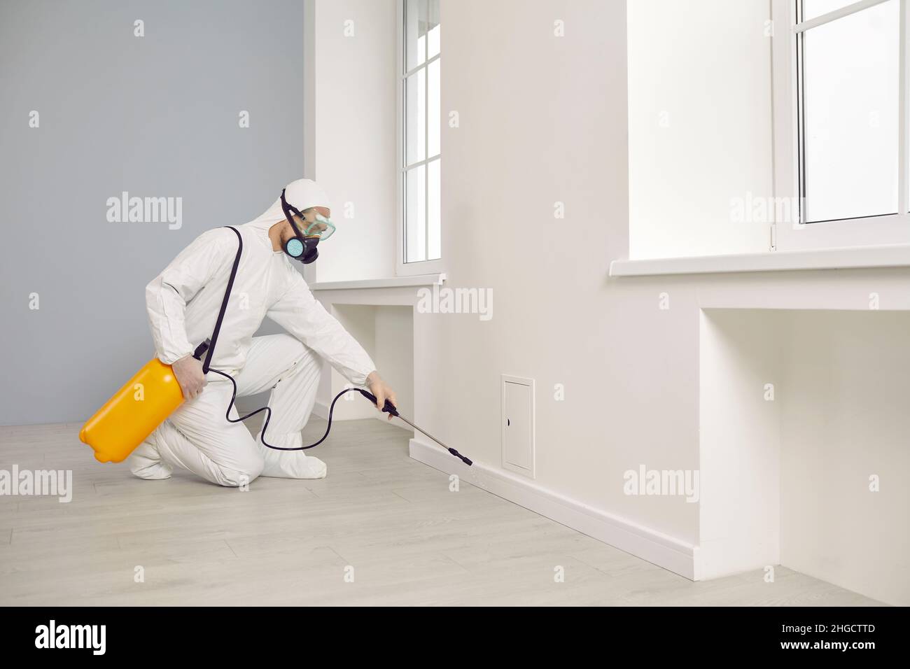 Pest control service worker in protective uniform spraying insecticide ...