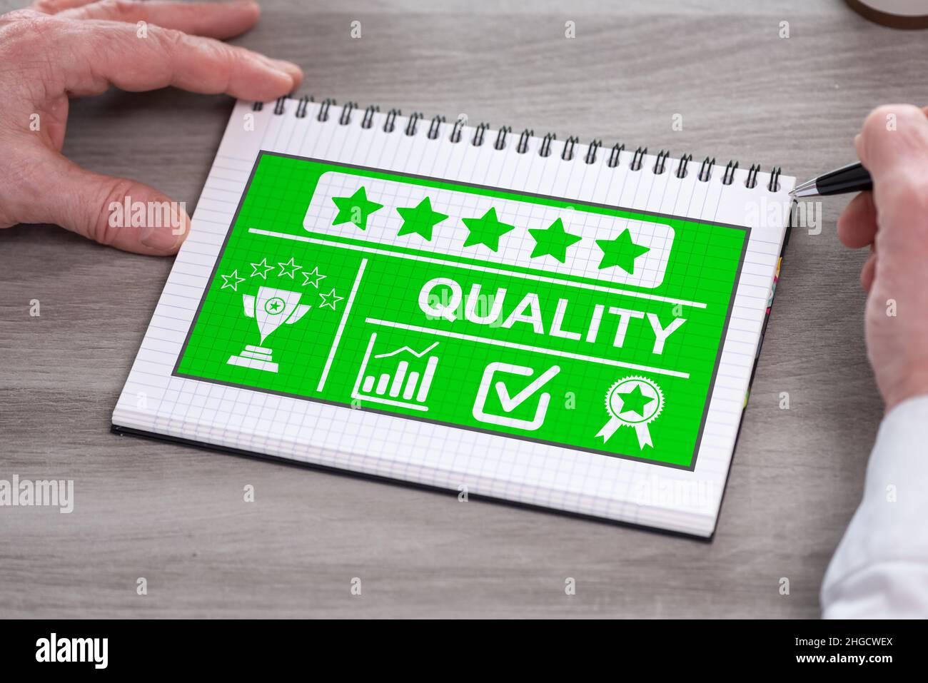 Hand holding a notepad with quality concept Stock Photo - Alamy