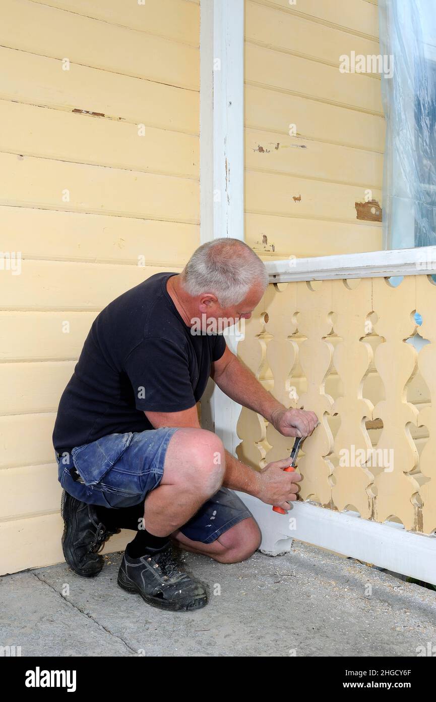 A man scraping old paint on a porch preparing for new paint Stock Photo ...