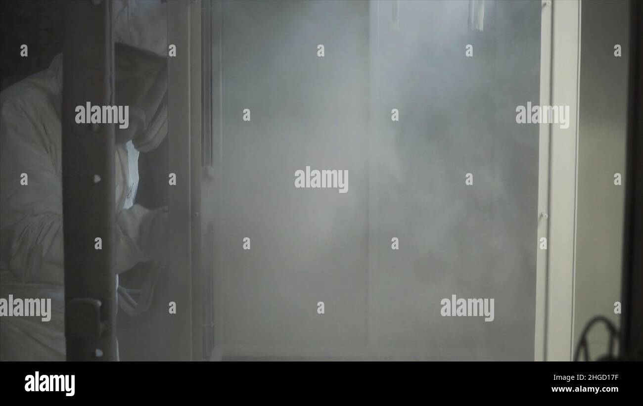 Worker at factory painting metal details with a gun of powder coating ...