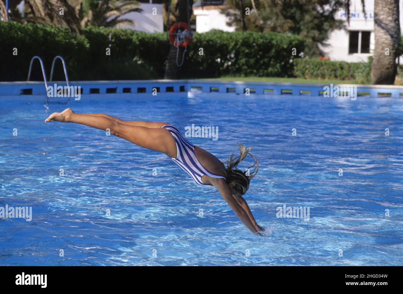 Athletic young woman in ray white blue bathin suit jumping in a ...