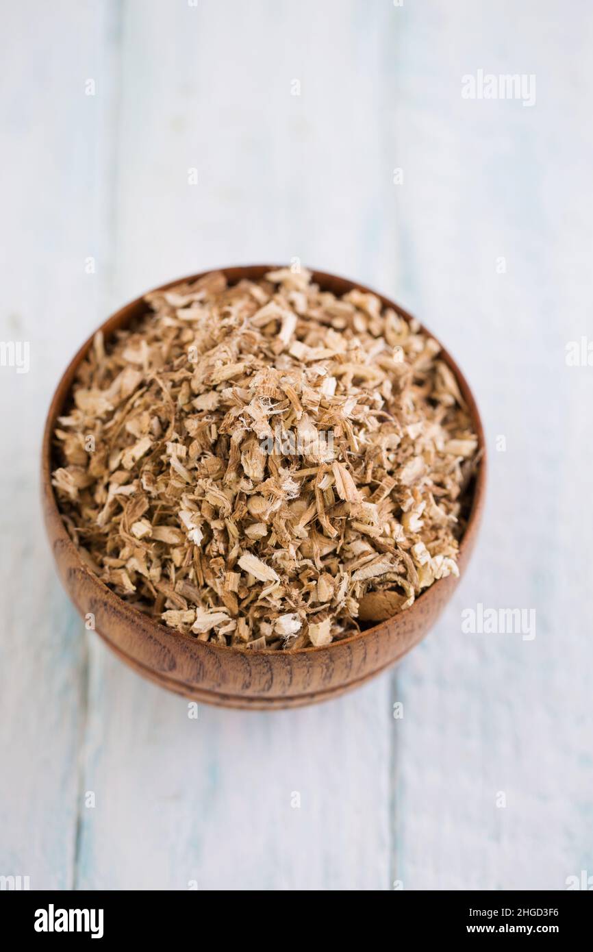 Chopped licorice root remedy with expectorant effect in a wooden bowl ...