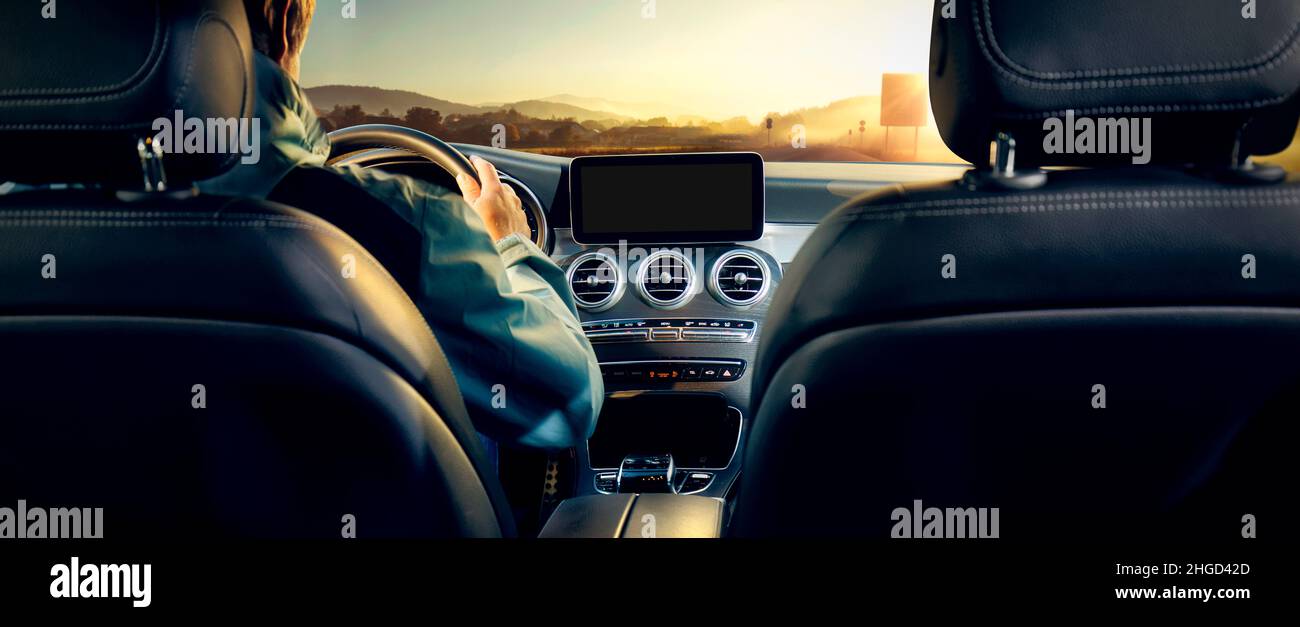 Panorama interior of a moving car with man behind the wheel at sunrise ...