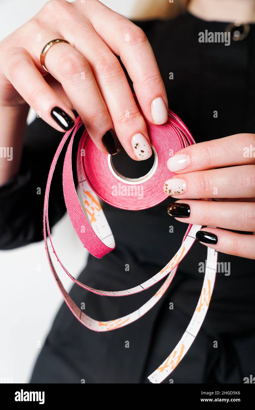 Young woman cosmetologist holding tape ribbon in the hands. Young doctor with kinesio tape ...