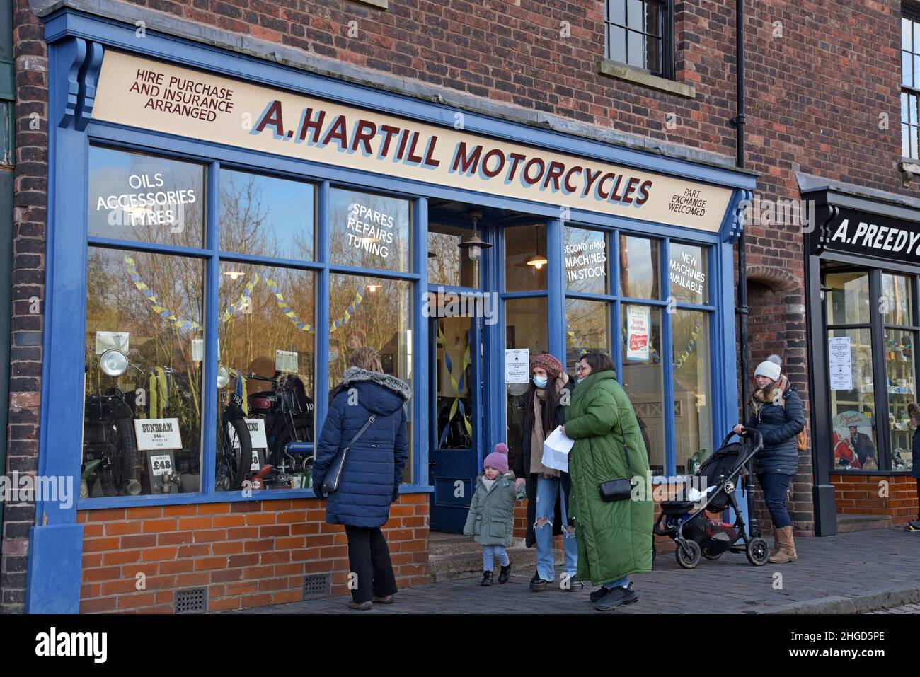 Visitors browsing the window of a motorcycle shop in the recreation of ...