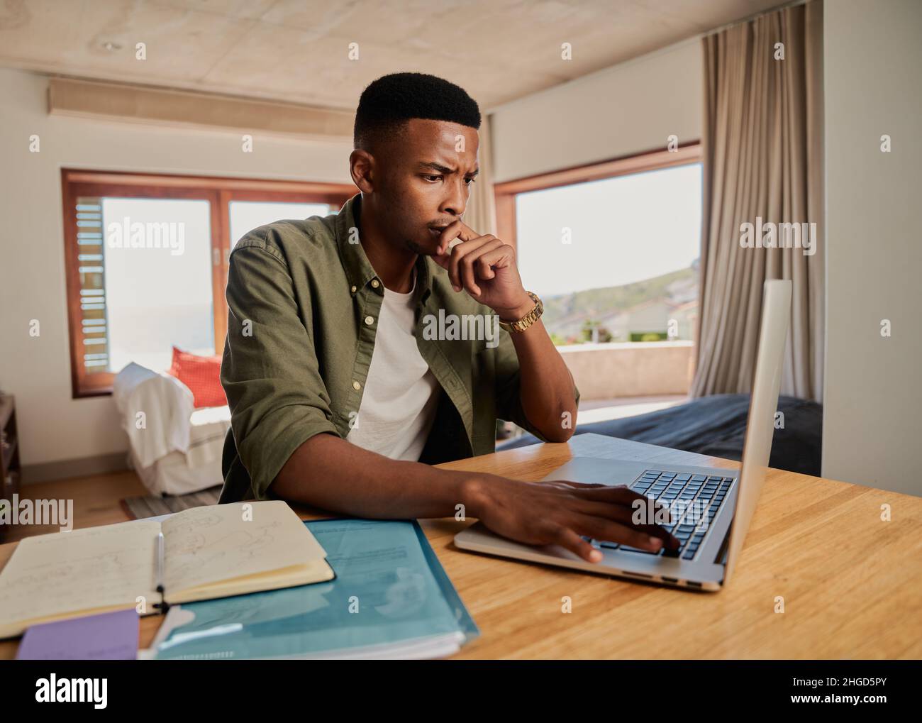 Young adult black male typing on his laptop, stressed. Sitting in ...