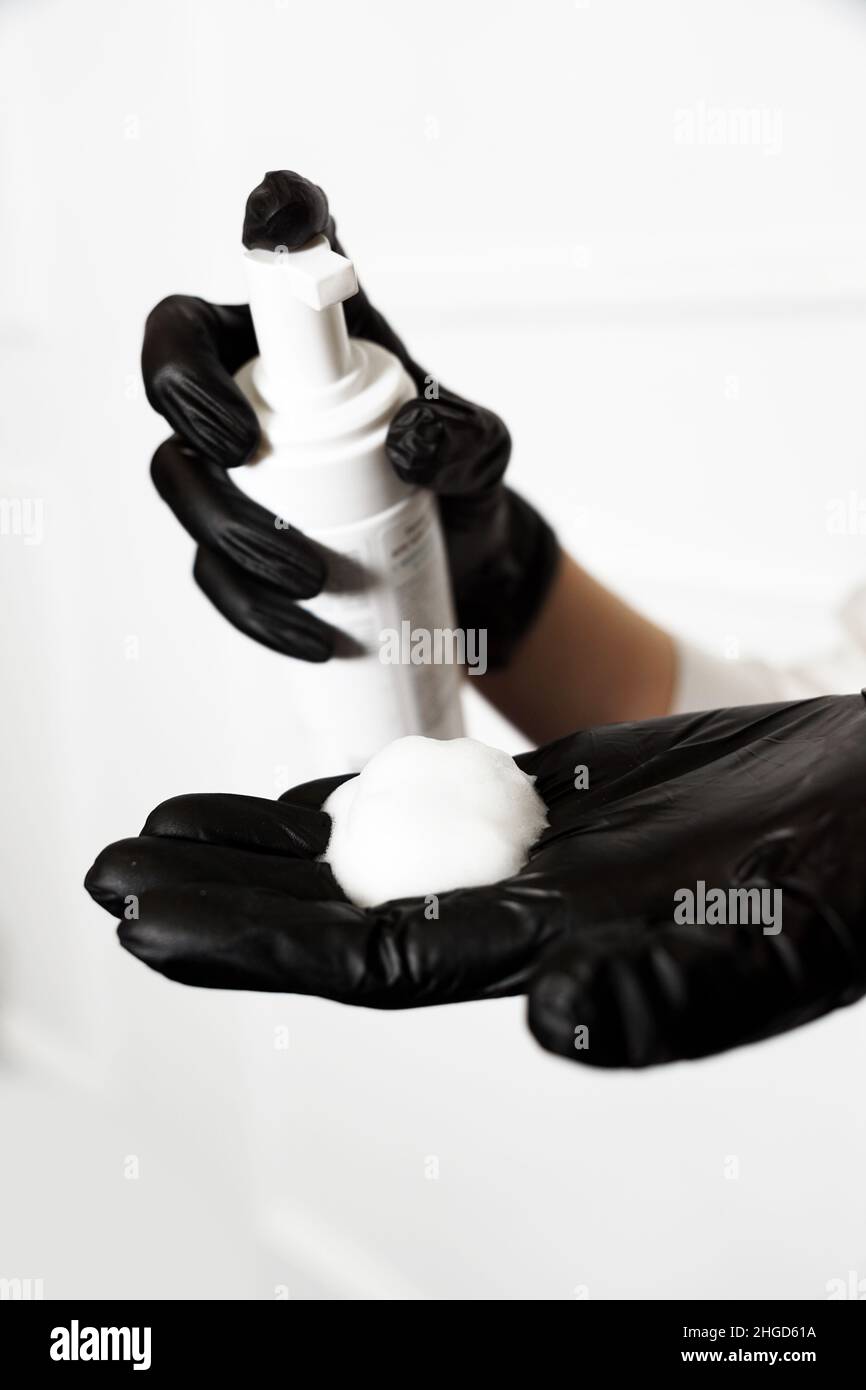 Closeup of a female hand with foam on the palm in black gloves. Woman ...