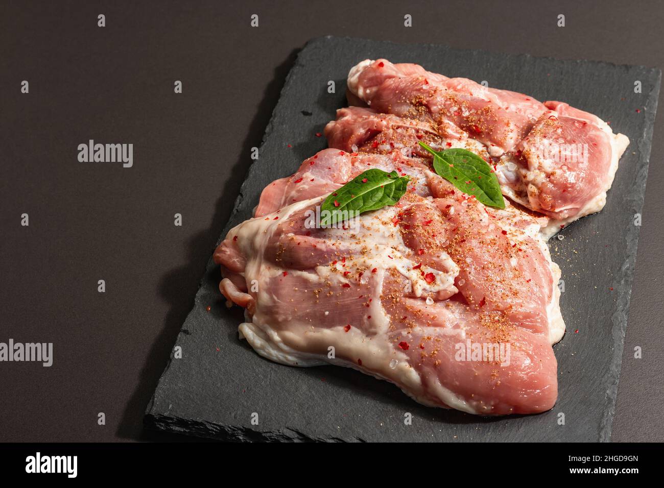 Raw turkey thigh with spices. Fresh boneless meat on a ceramic stand ...