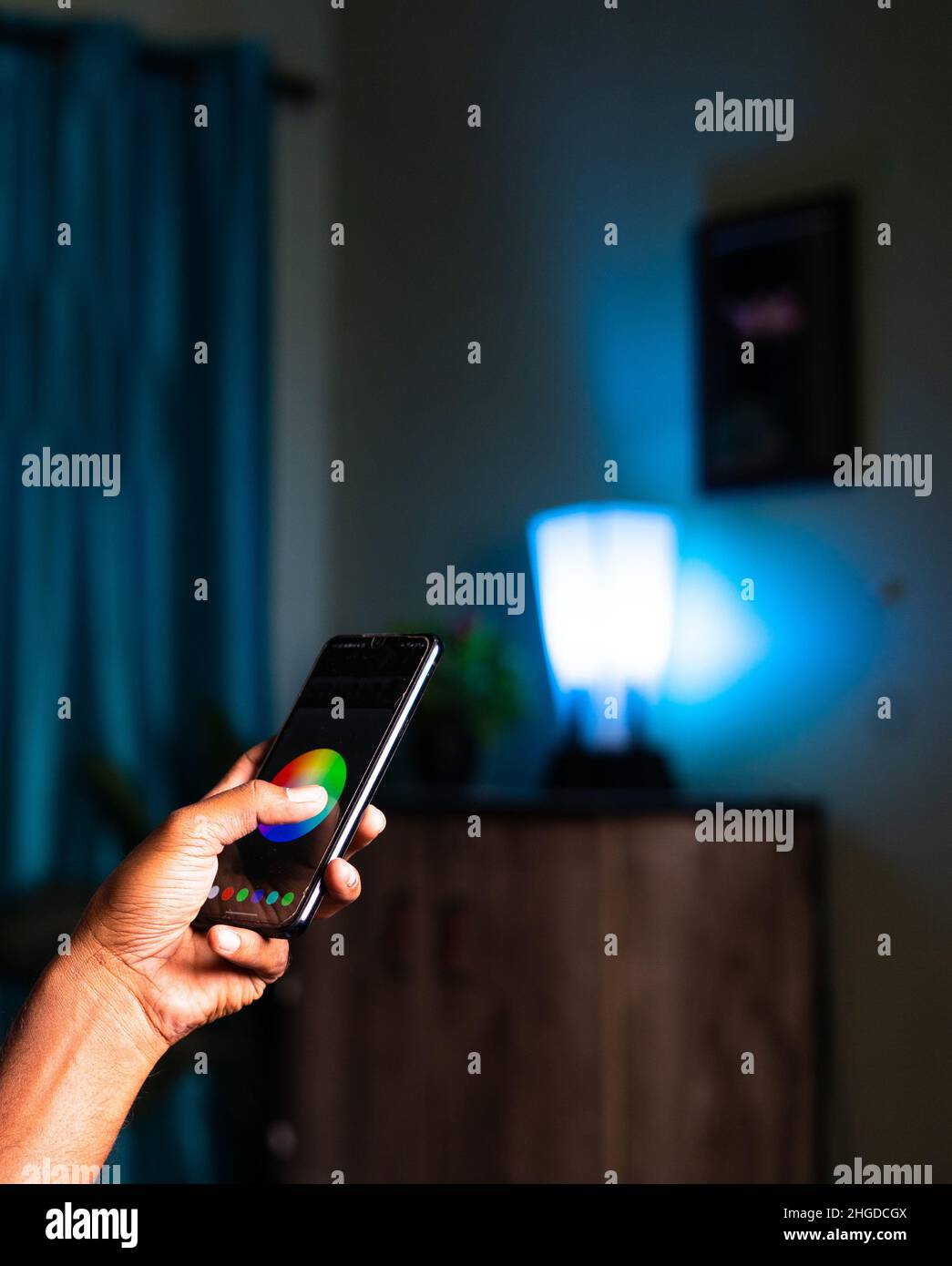 Close up shot unrecognizable person controling smart bulb using mobile ...