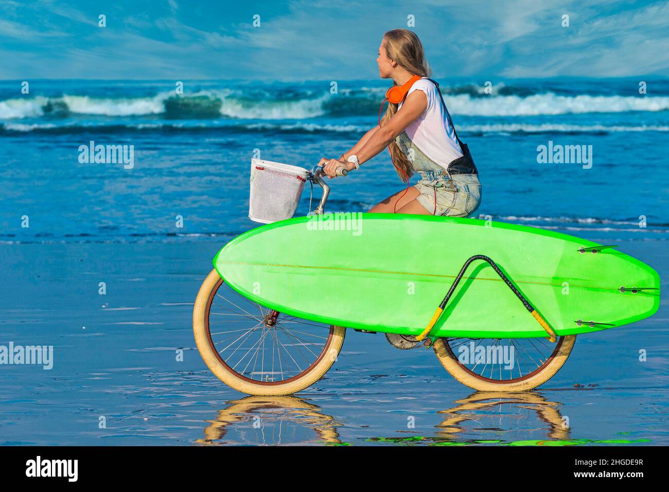 Young woman with surfboard and bicycle on the beach Stock Photo - Alamy