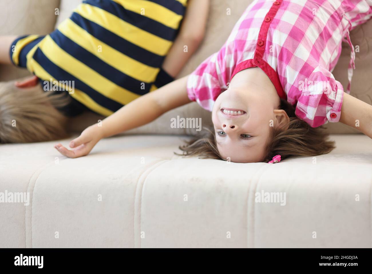 Children have fun at home, kids upside down on sofa, holiday at school ...