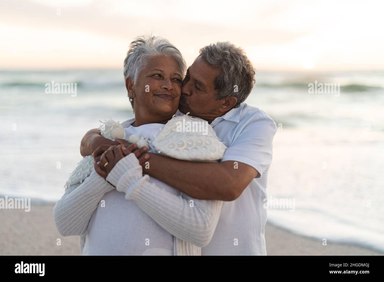 Affectionate senior biracial man kissing while hugging woman from ...