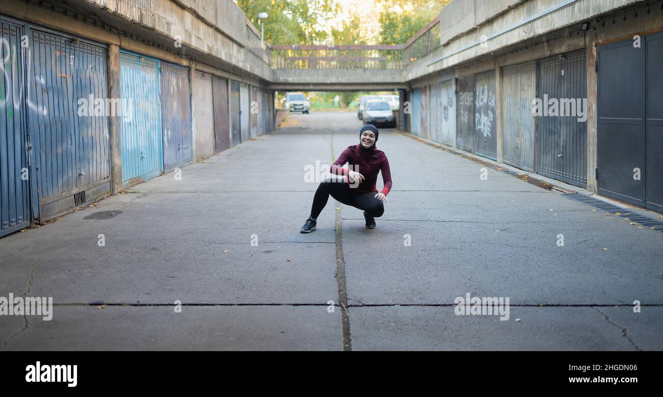 Muslim woman with a hijab laughing while stretching in the streets ...