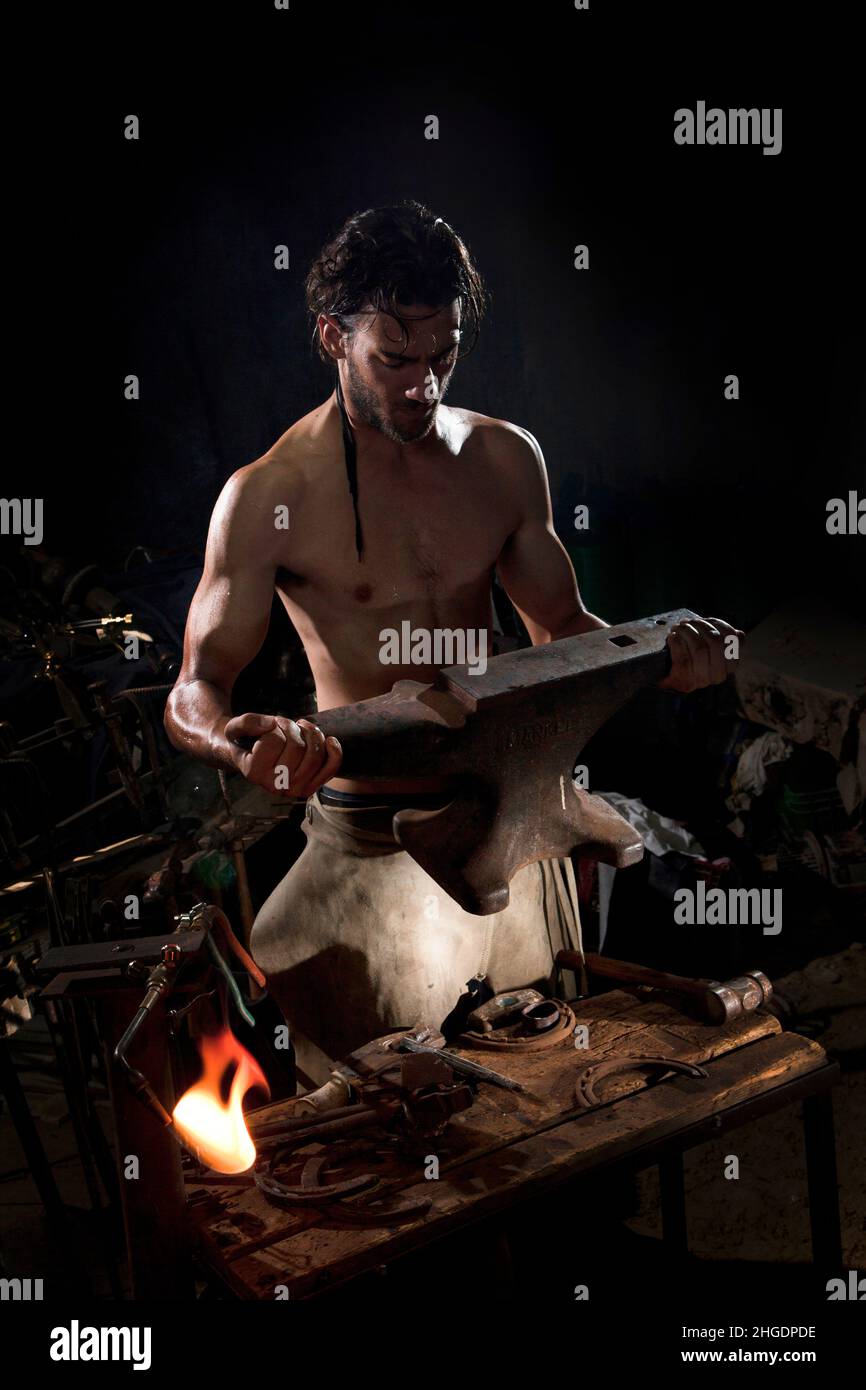 manual labour Blacksmith works in a dark workshop Stock Photo - Alamy