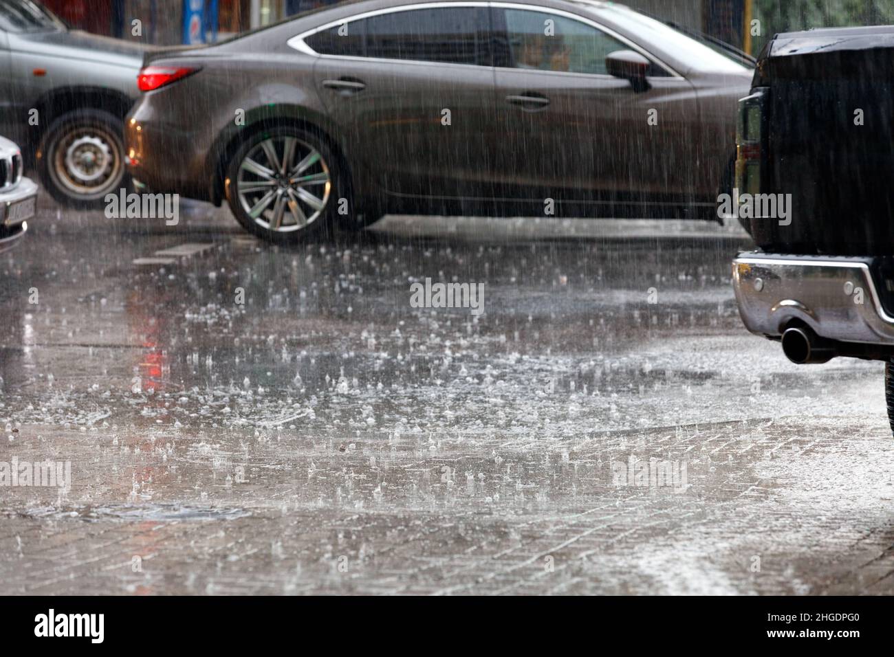 Heavy rain falls on passing cars on a city road. Blurred rain ...