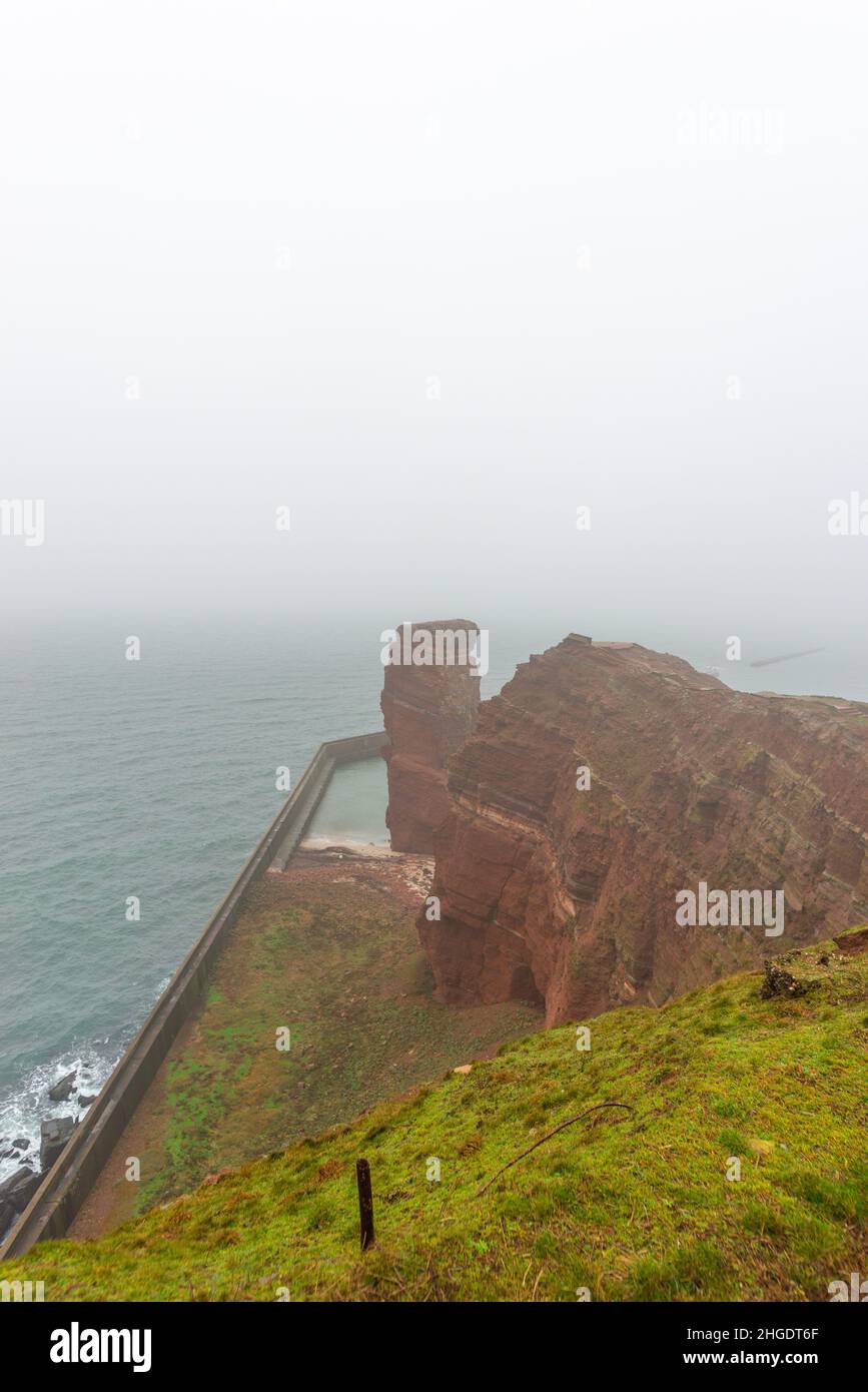 Steep red sandstone cliffs with single cliff "Lange Anna" in dense fog ...