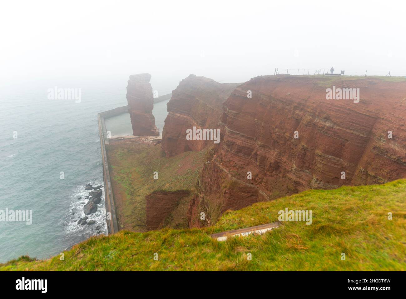 Steep red sandstone cliffs with single cliff "Lange Anna" in dense fog ...