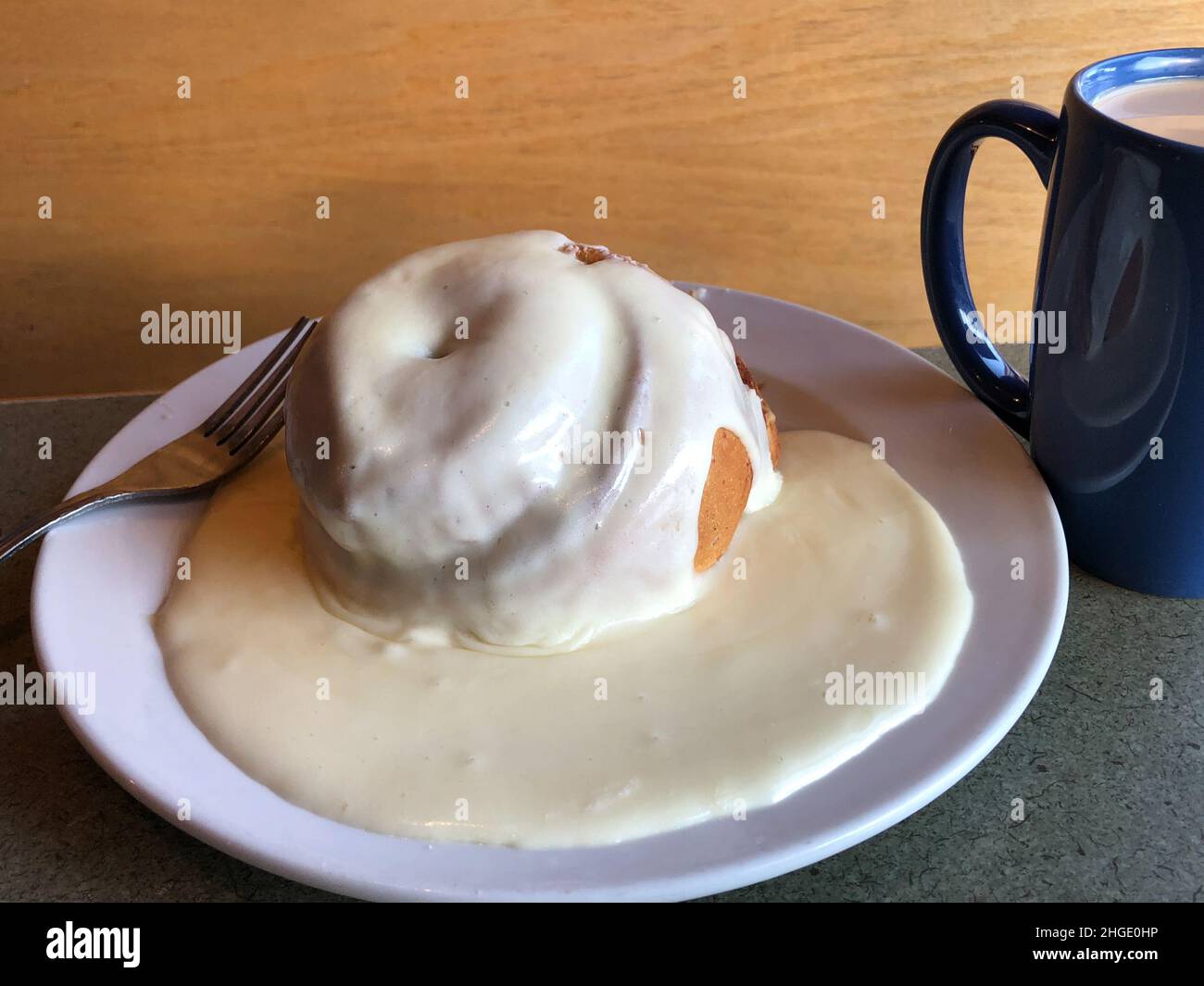 Cinnamon Bun covered in gooey icing with a cup of coffee Stock Photo ...